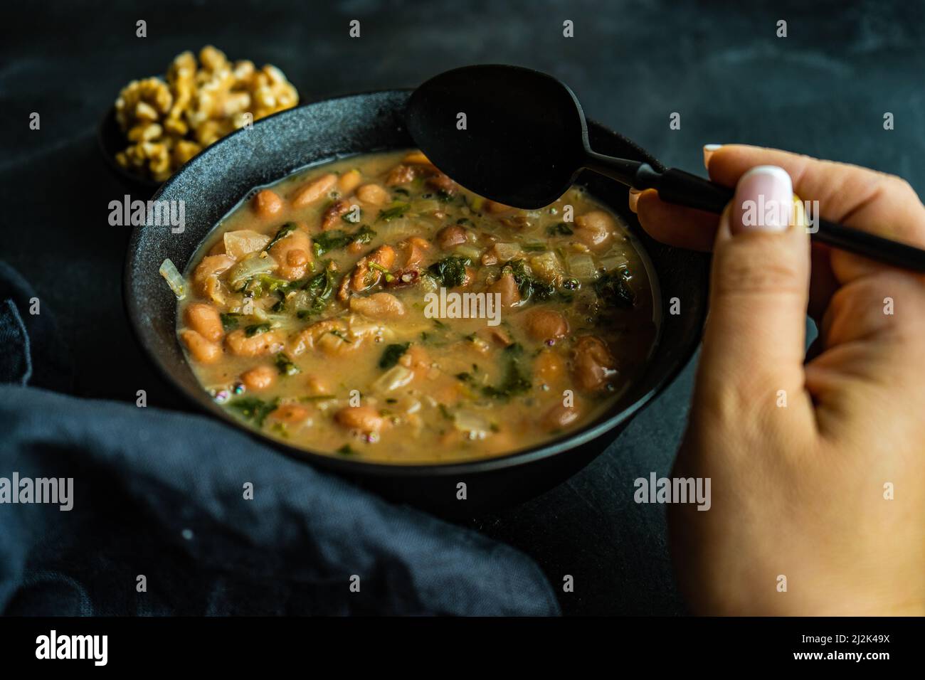 Woman eating a bowl of traditional Georgian lobio with walnuts Stock ...