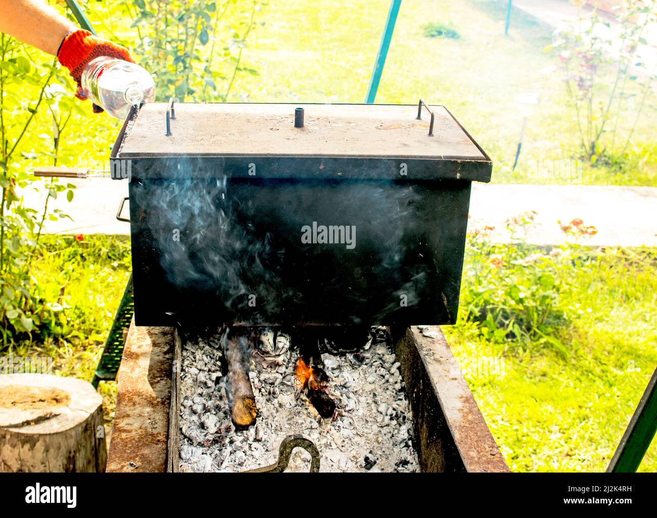 Smokehouse for hot smoking on fire. A man pours water into the shutter ...