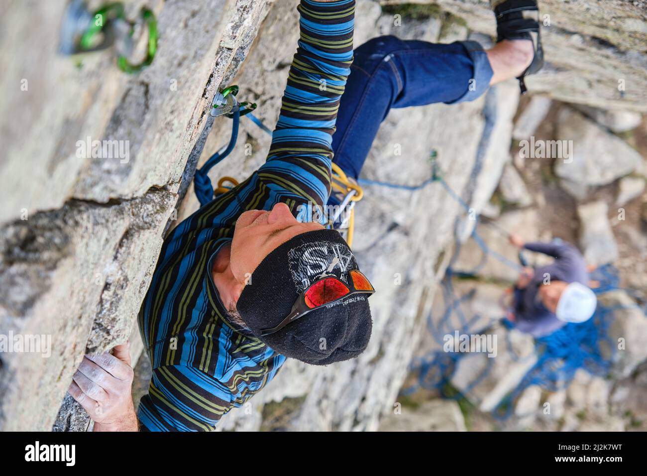 A Man reaching for a grip while he rock climbs on a steep cliff Stock ...