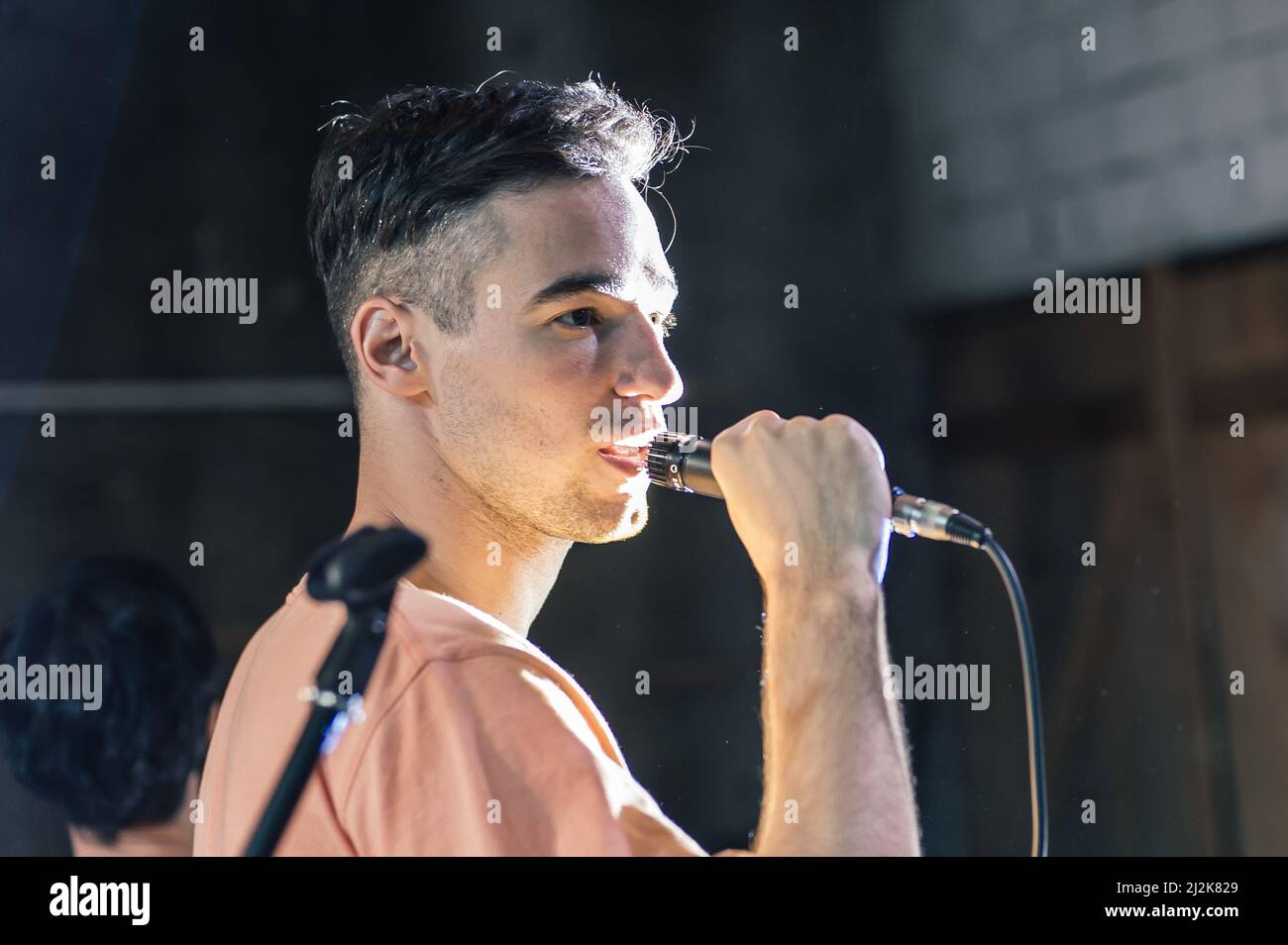 Smiling and witty stand up actor comedian on stage, talking and singing ...