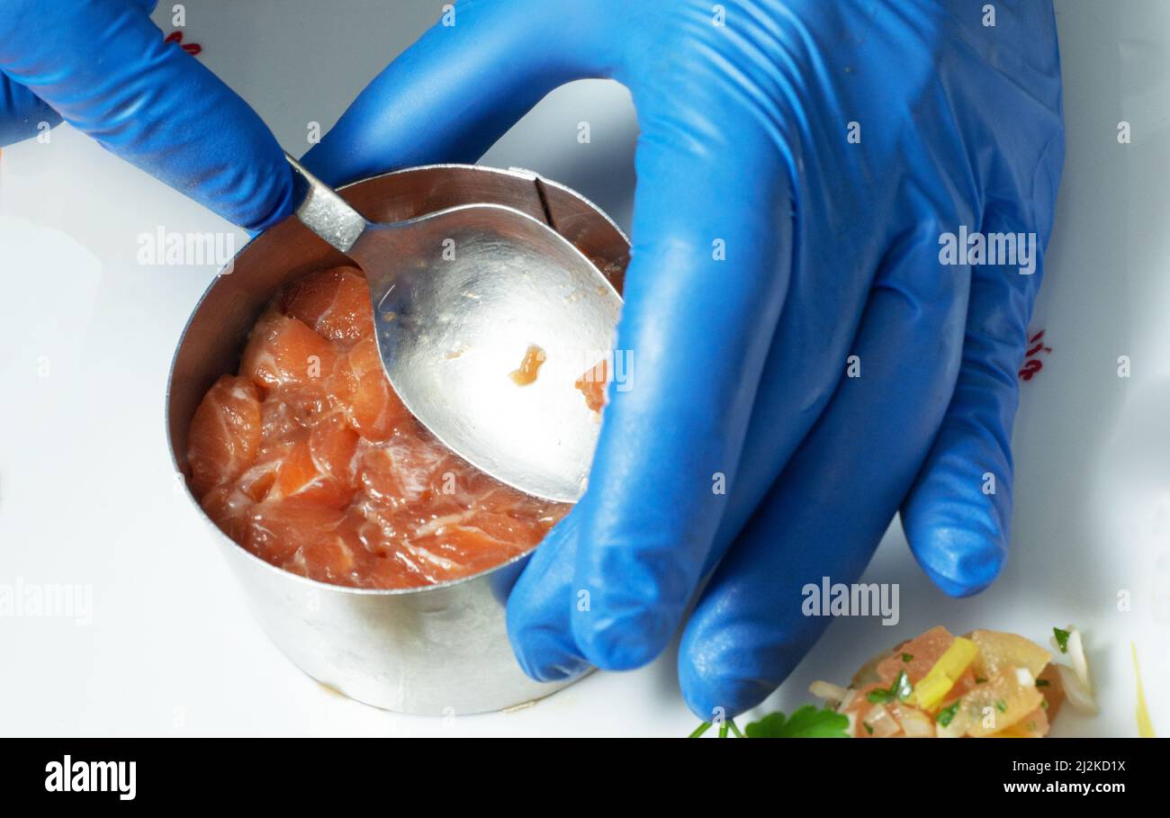 A top view of the chef preparing salmon tartar using a mold and a spoon ...