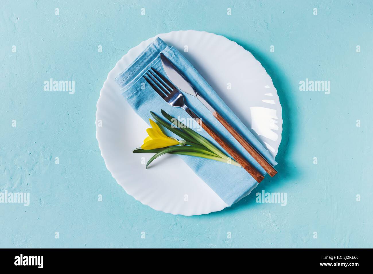 Spring table layout with plate and tableware on pastel blue background ...