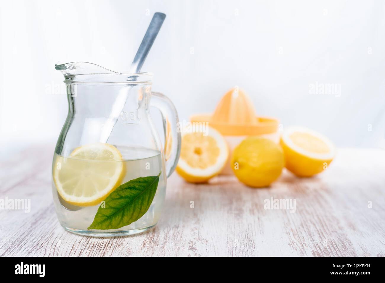 Pitcher with lemonade and cubes, a slice of lemon and a green leaf, in ...