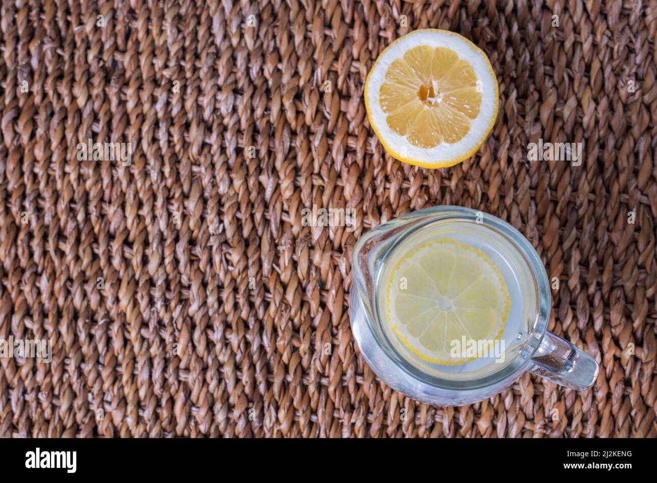 Pitcher of lemonade with a slice of lemon on top, accompanied by half a ...