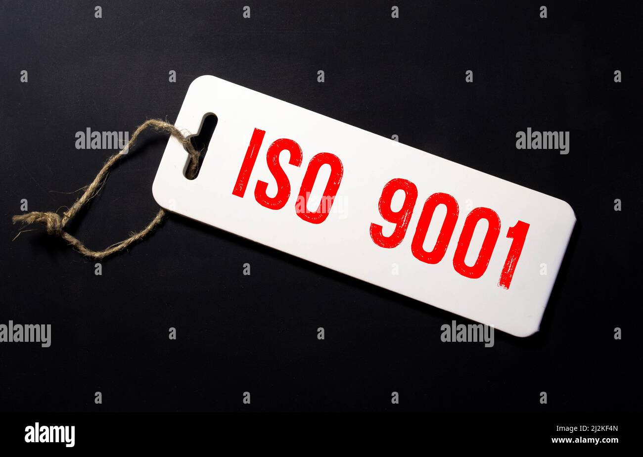 Notebook with text inside ISO 9001 on table with coffee, mobile phone ...