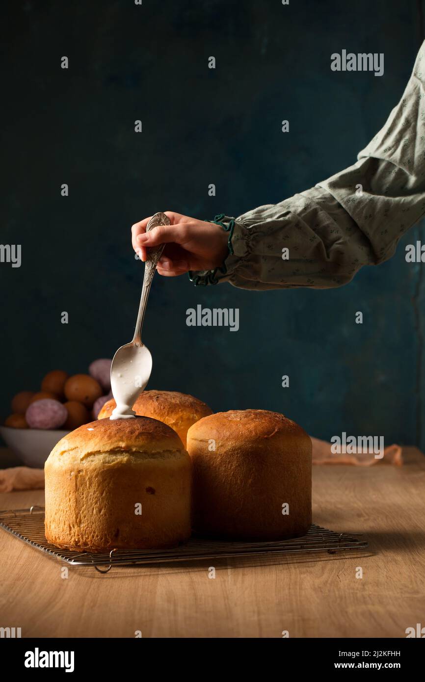 A girl smears Easter cakes with icing, photo in a rustic style Stock ...