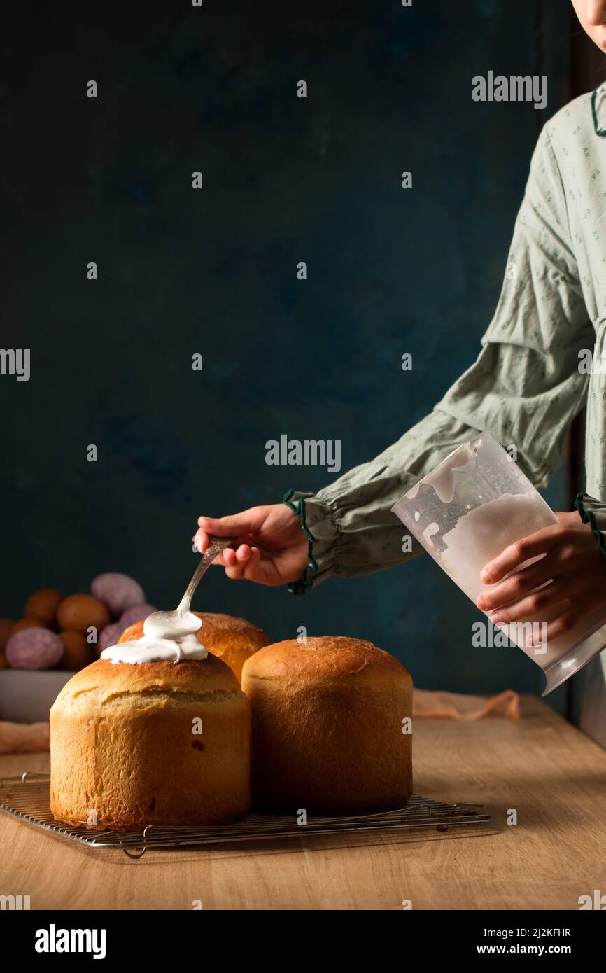A girl smears Easter cakes with icing, photo in a rustic style Stock ...