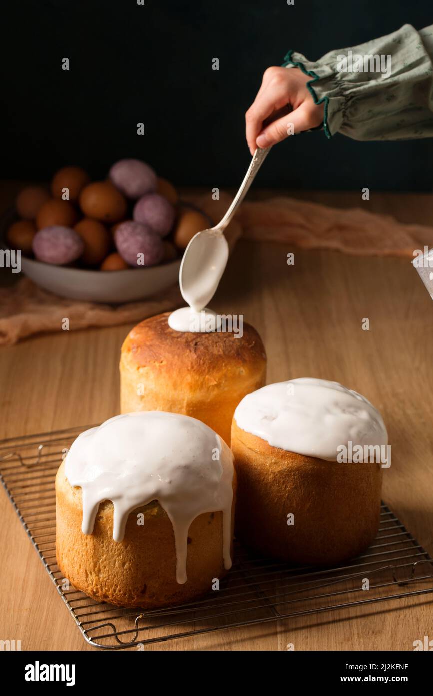 A girl smears Easter cakes with icing, photo in a rustic style Stock ...