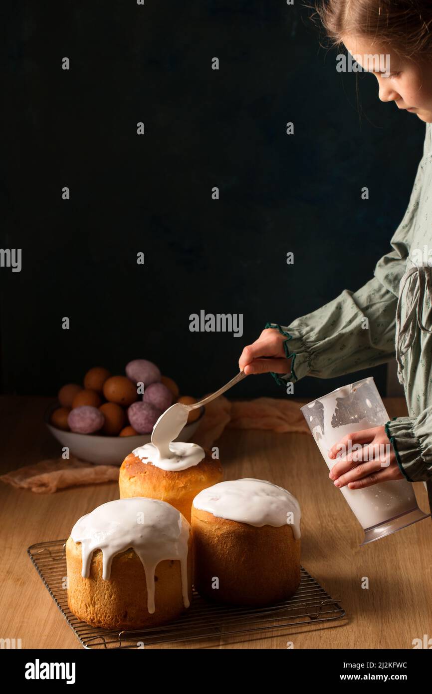A girl smears Easter cakes with icing, photo in a rustic style Stock ...