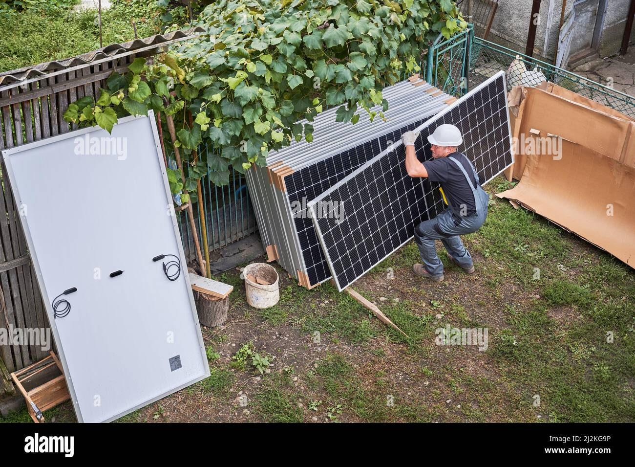 Man worker lifting up photovoltaic solar moduls on roof of house ...
