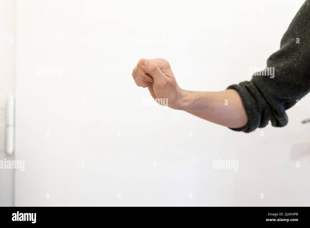 A shot of a man's hand in a door knocking position on a white ...