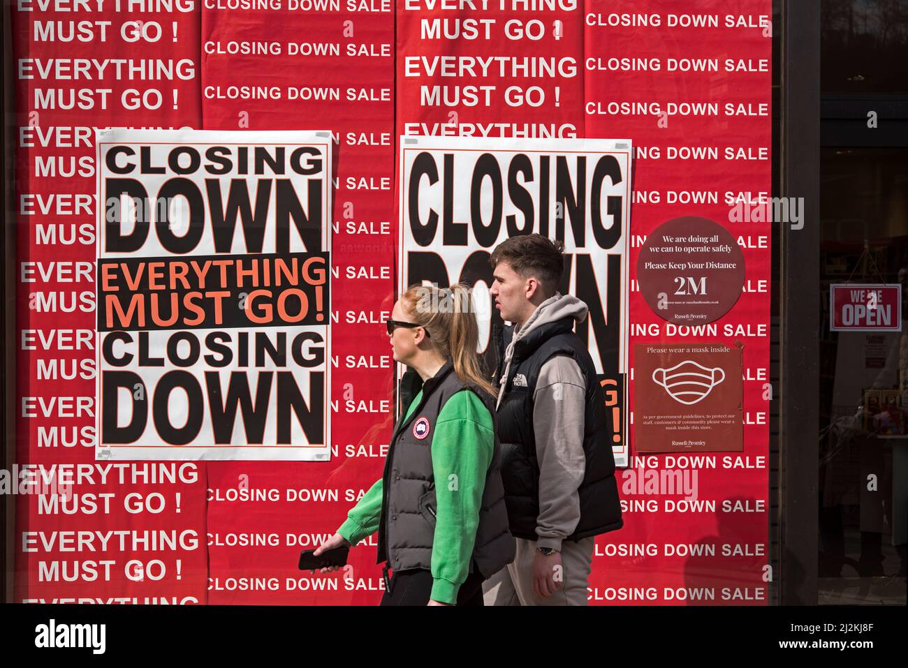 Couple walking by "Closing Down", Everything Must Go" signs in the ...