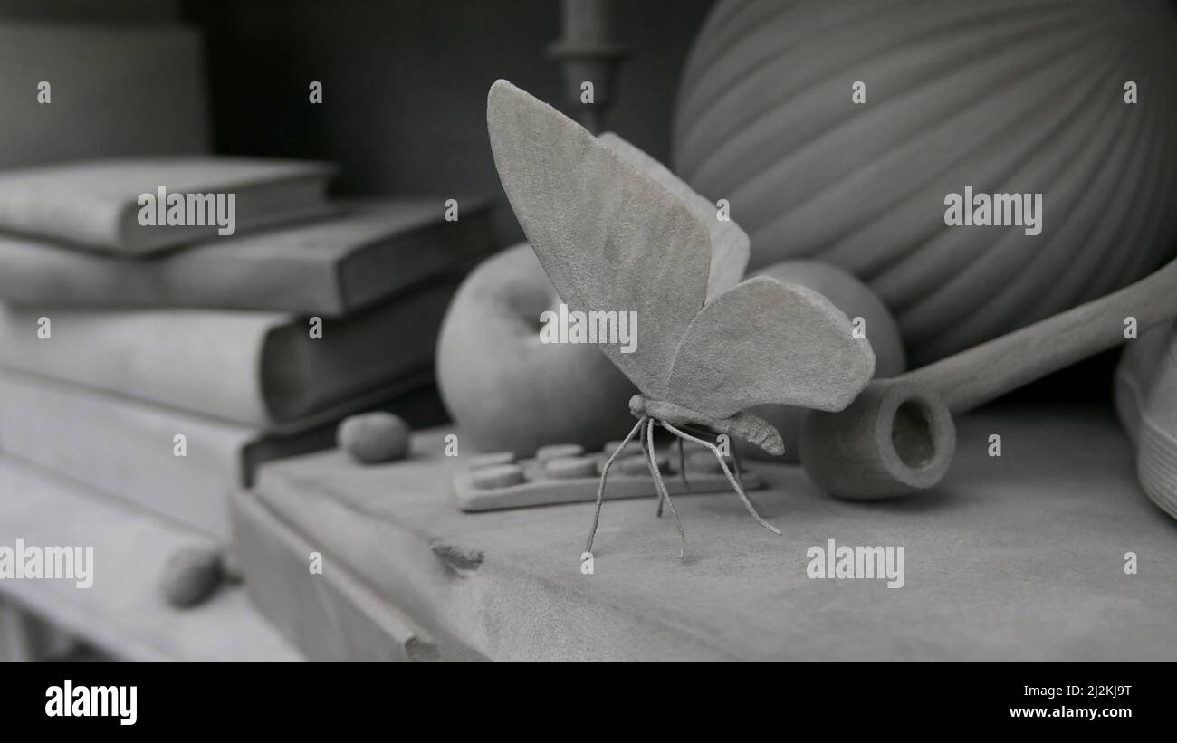 A grayscale of a gray butterfly, apple and blurred books on the table ...