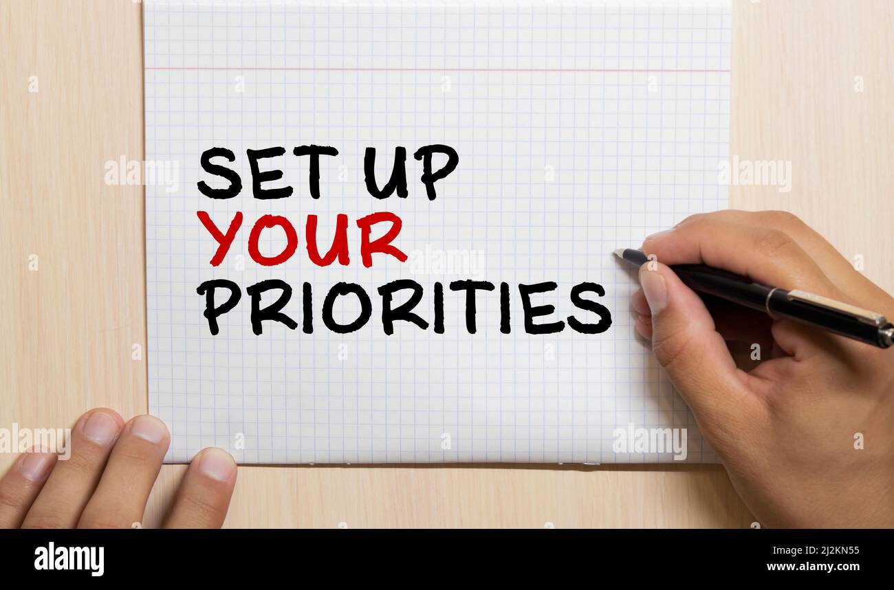 Laptop, red pen and notepad with text Set up your priorities in the ...