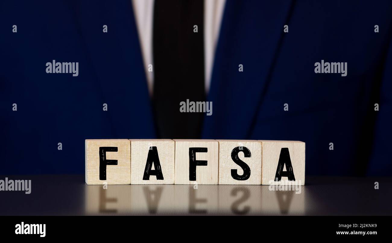 A wooden blocks with the word FAFSA written on it on a gray background ...