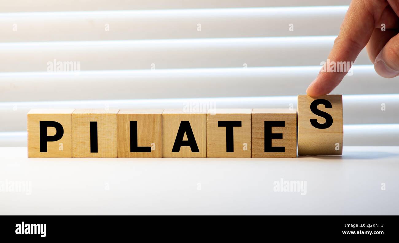Pilates text on wooden cubes on a brown cork background Stock Photo - Alamy