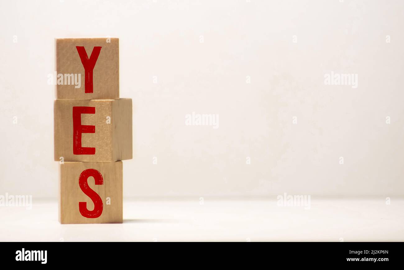 Word YES is made of wooden building blocks lying on the table and on a ...