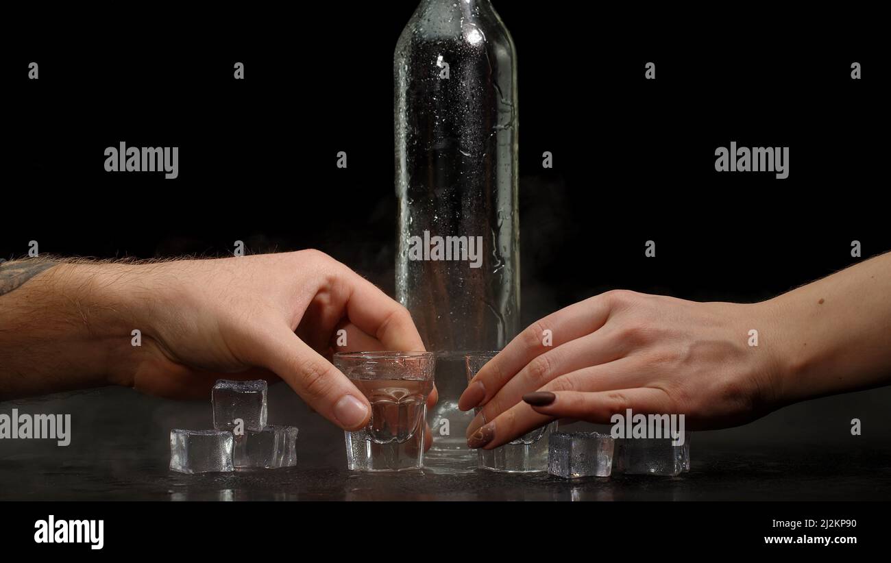 Two hands with glasses of vodka making cheers, raising toast on black ...