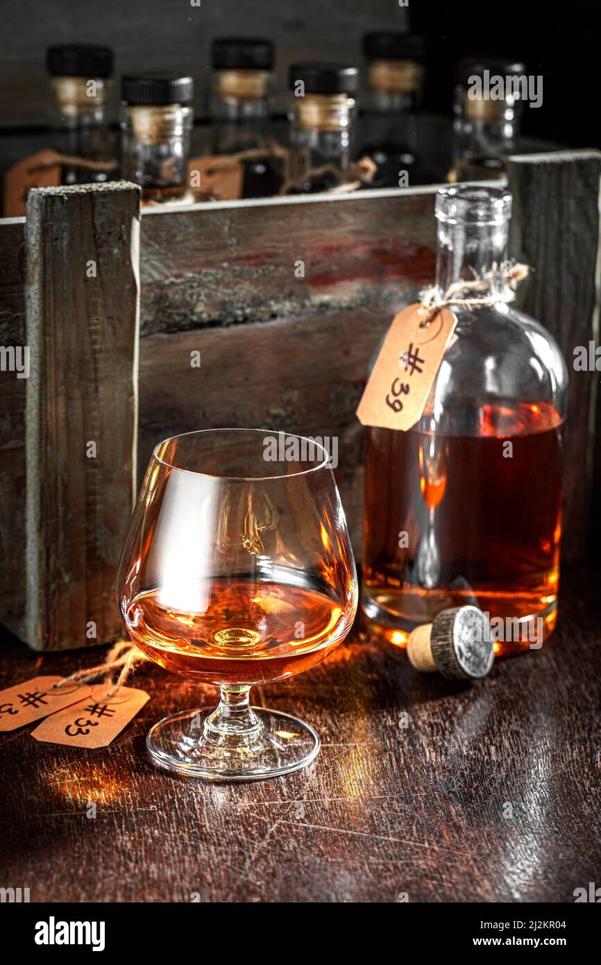 Old and golden whisky with ice in a glass in the distillery. Glass of ...