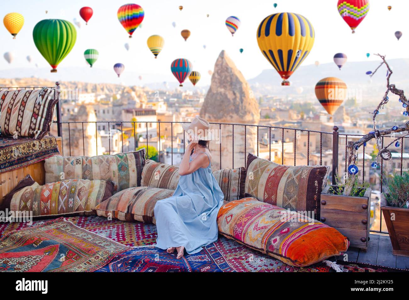 Young woman in Cappadocia. Woman on a rooftop with air balloons in ...