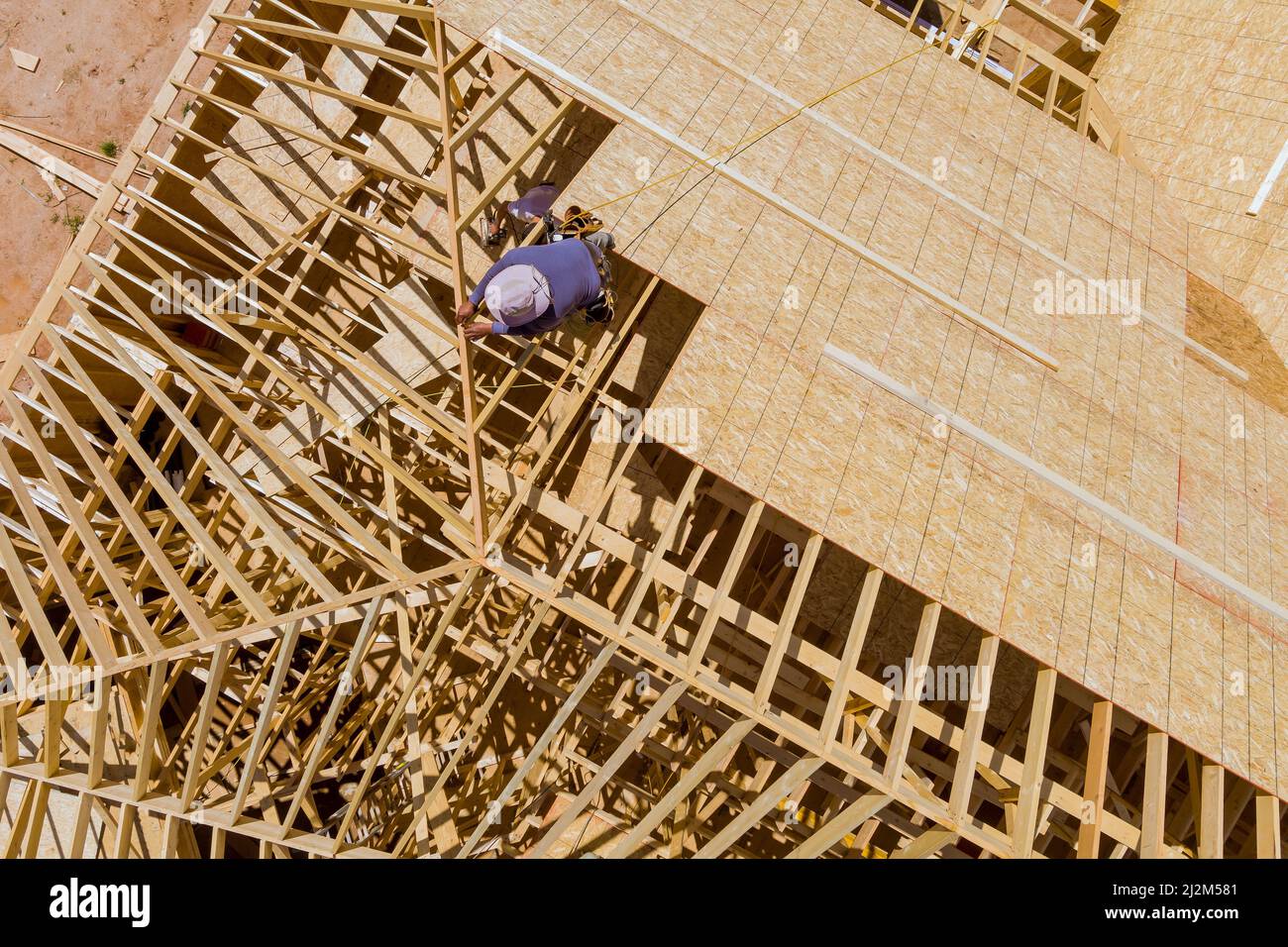Aerial top view of carpenter with plywood nailing on roof of in ...