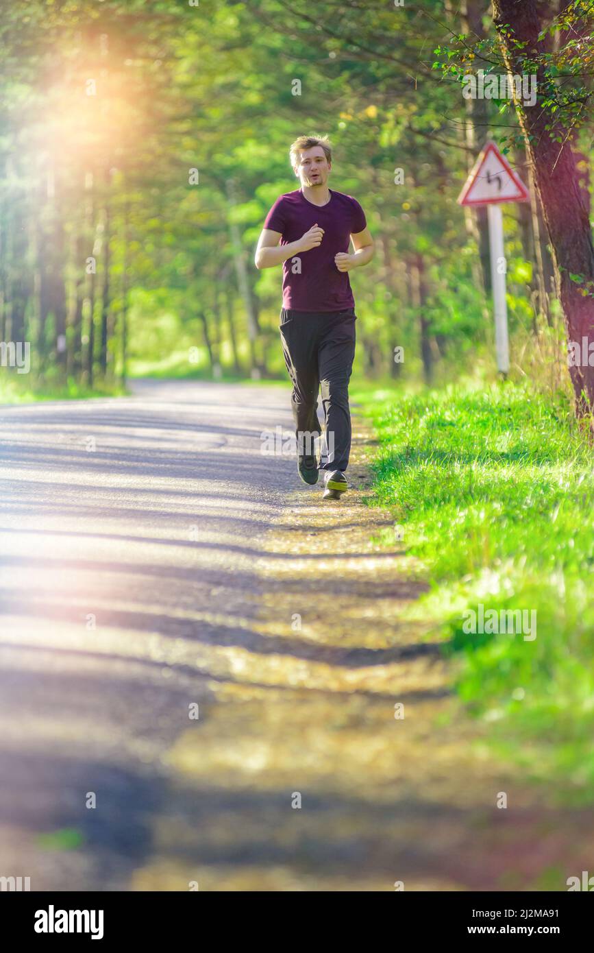 Running man jogging in city park at beautiful summer day. Sport fitness ...
