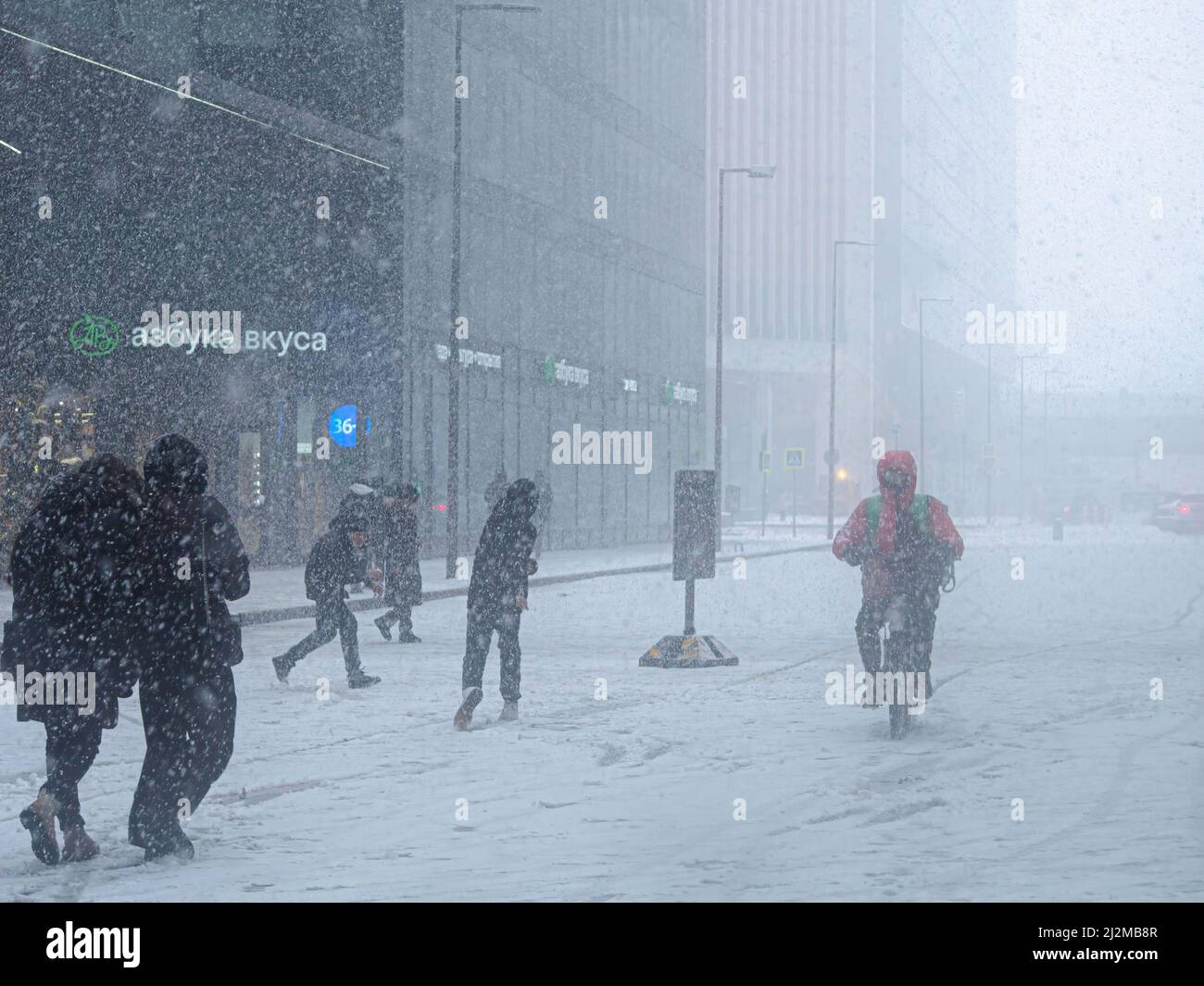 People walk on a snow covered street during heavy snowfall. Cyclone ...