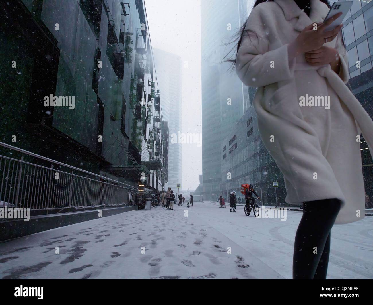 People walk on a snow covered street during heavy snowfall. Cyclone ...