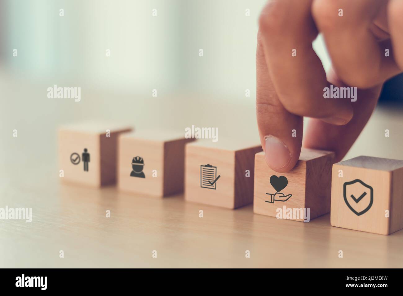 Safety at work concept. Hand holds cubes wooden block with safety icons ...