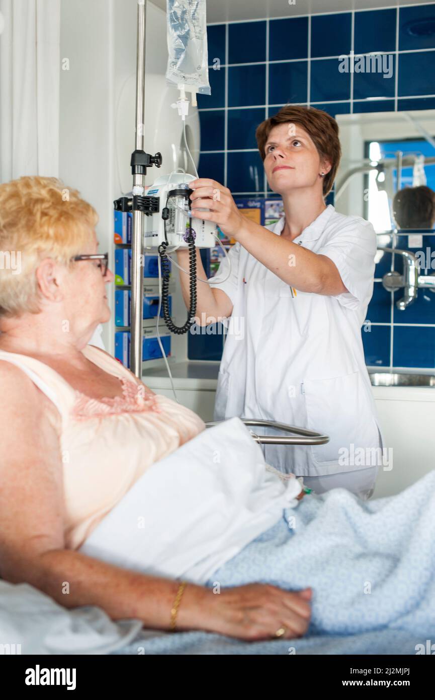 Nurse preparing an IV for a patient in bed Stock Photo - Alamy