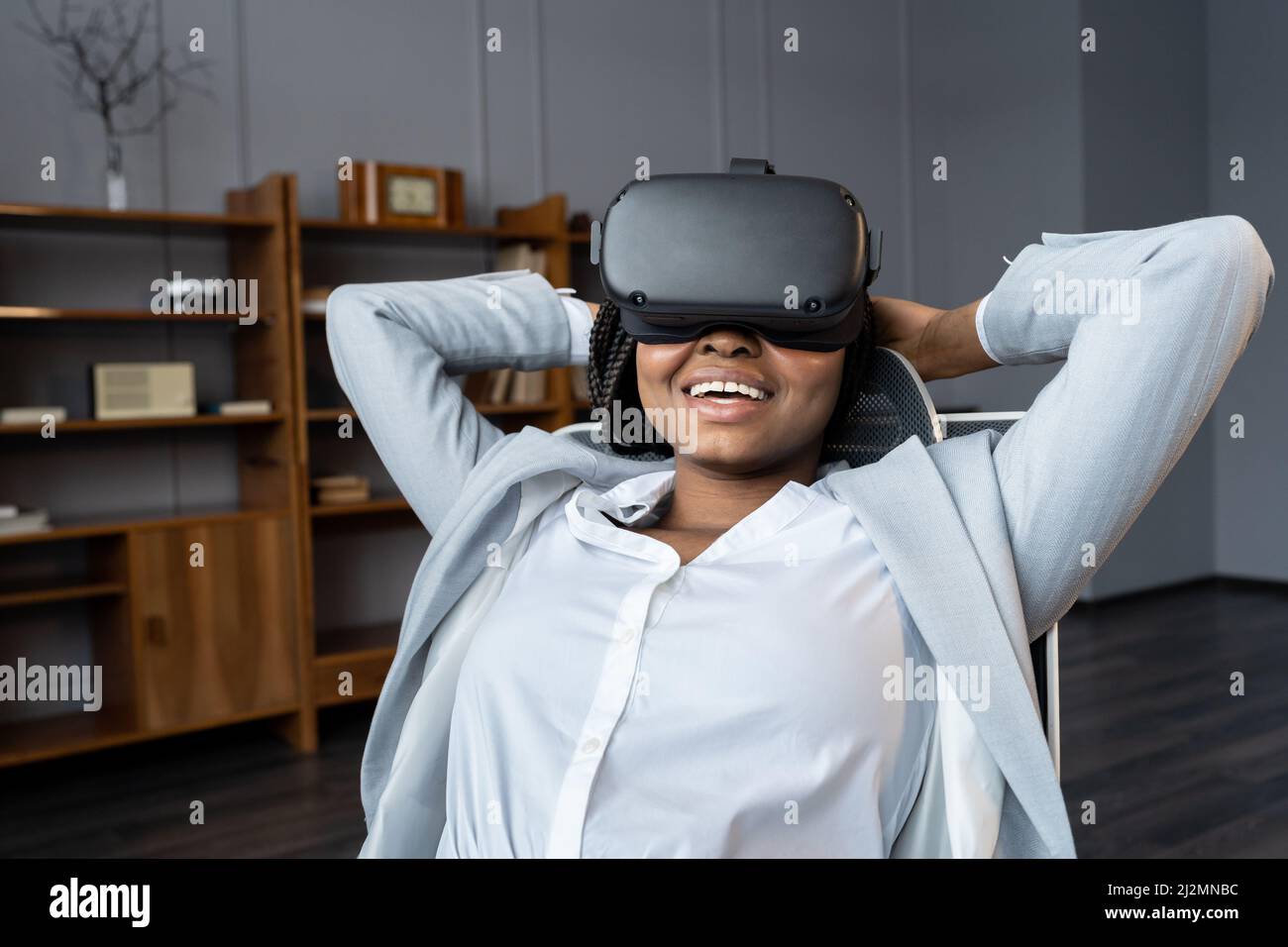 Relaxed woman wear vr goggles headset sit at office desk experiencing ...