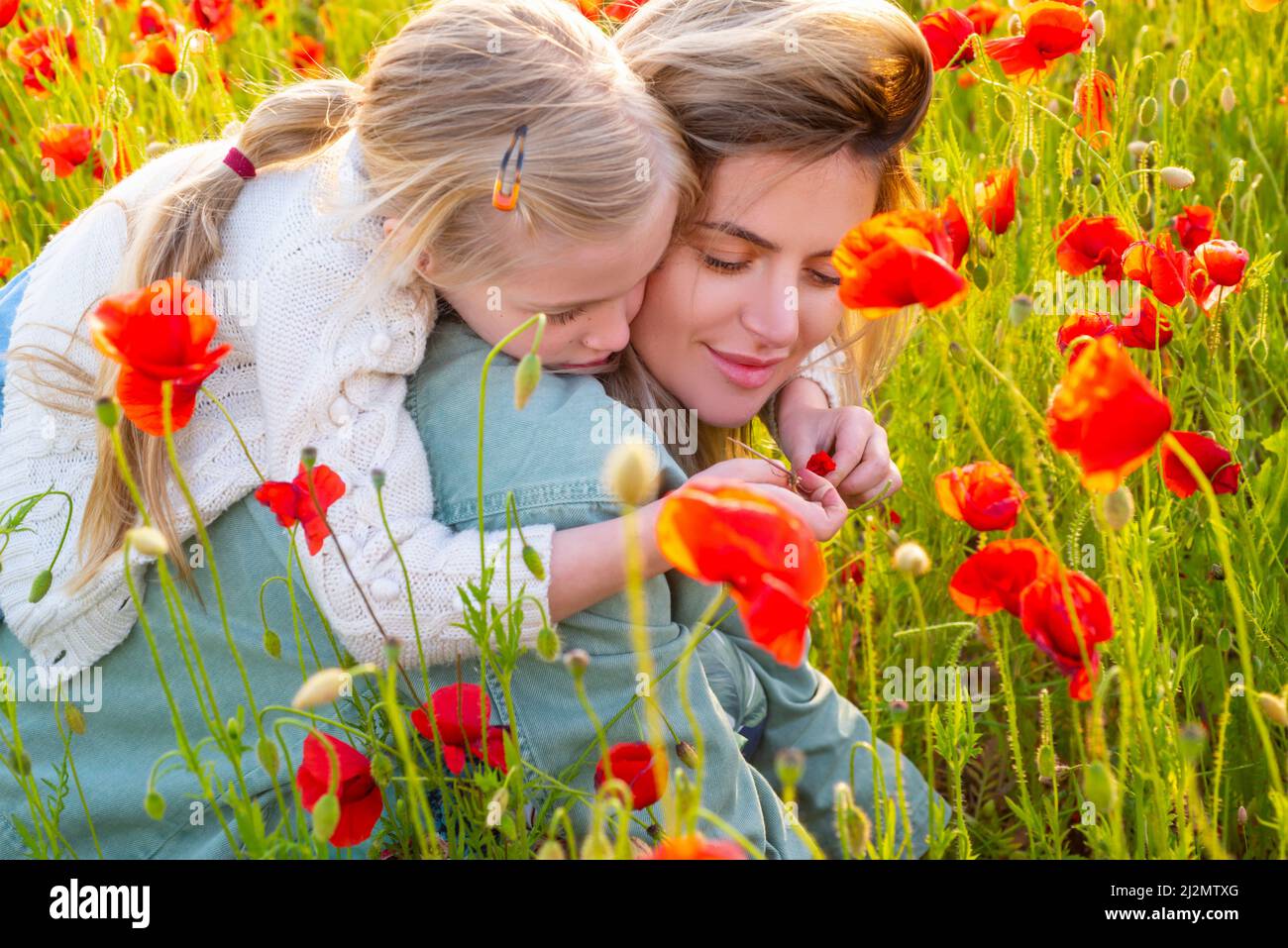 Mother and daughter hugging in a poppies meadow. Mom and child girl ...