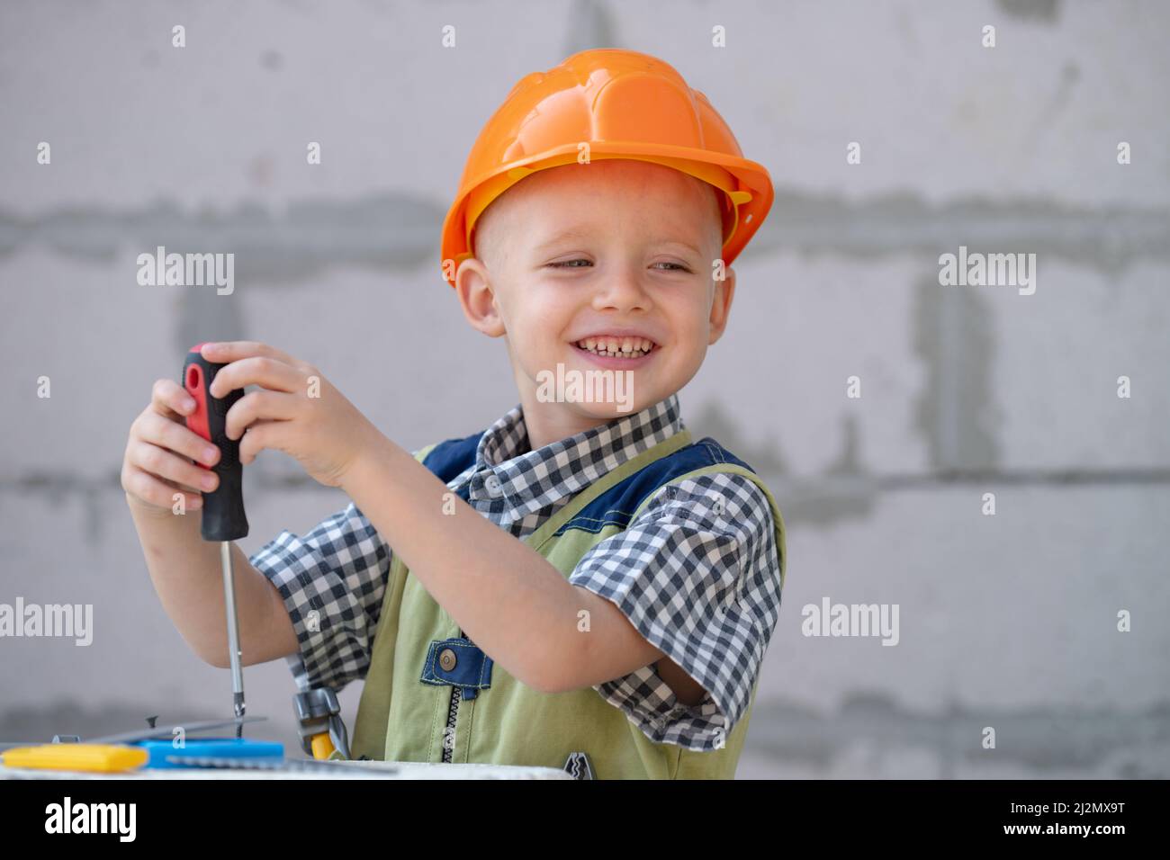 Little boy holding screwdriver. Happy smiling kid twists bolt with ...