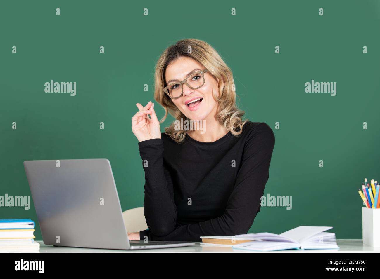 Young female teacher with pointing finger on lesson at blackboard in ...