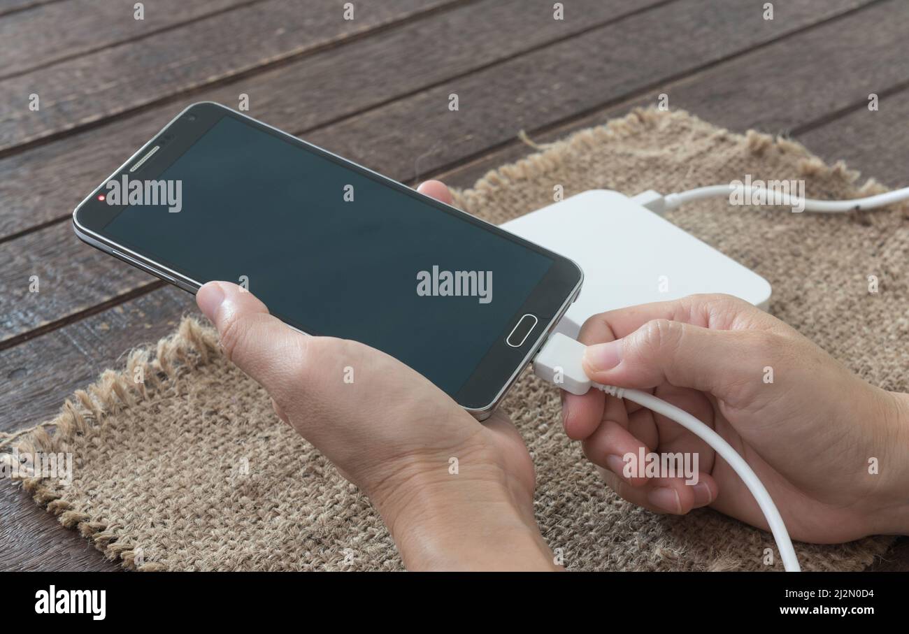 woman are connected charging cable to the smartphone by external ...