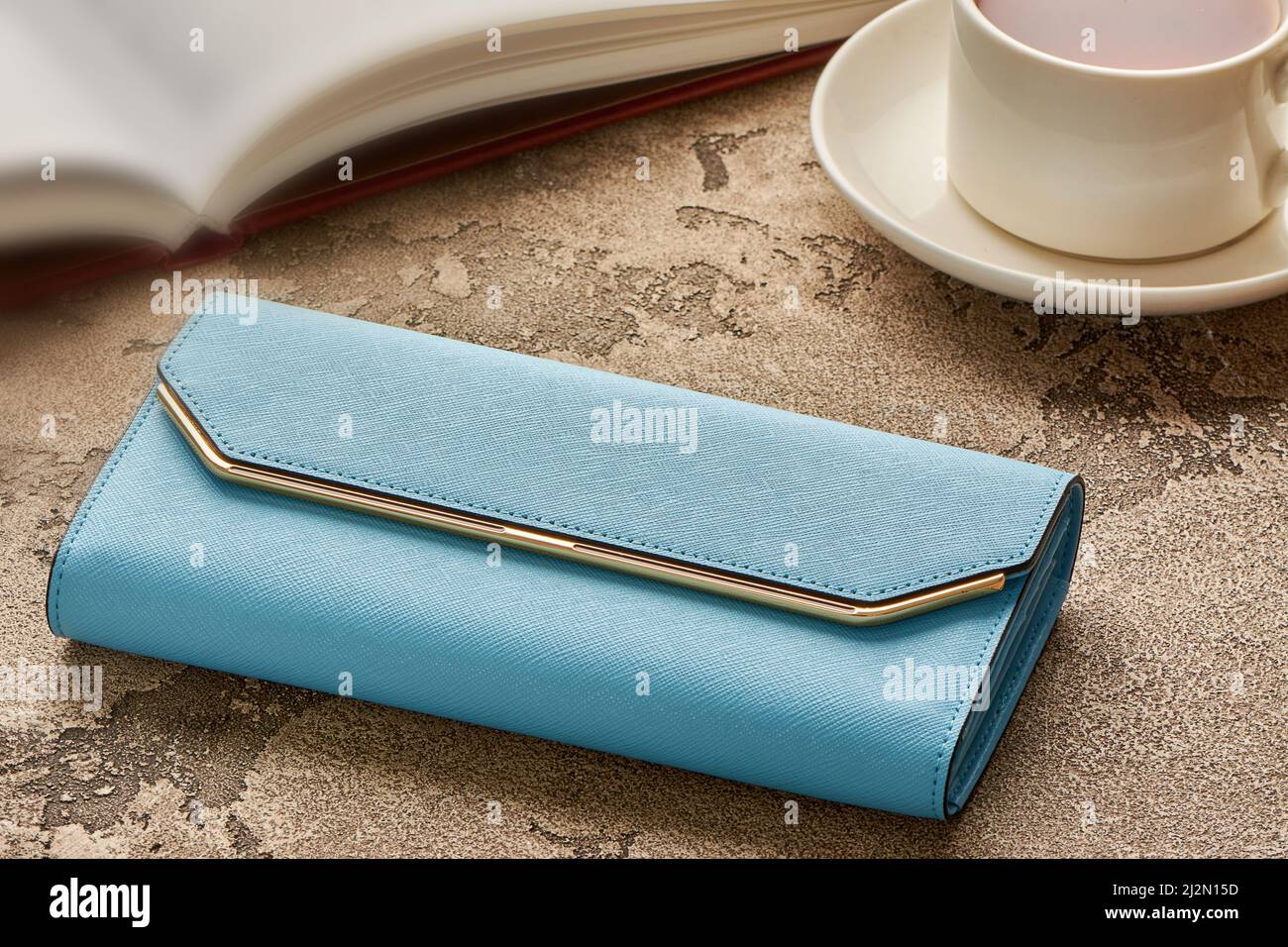 A blue woman's purse lies on a concrete background with a cup of coffee ...