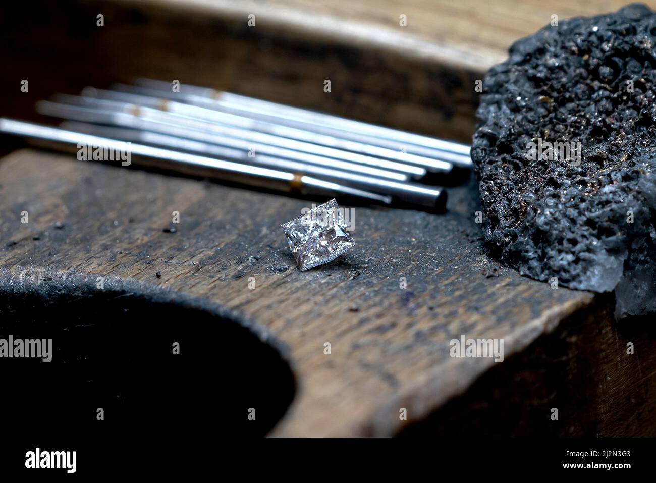A princess cut diamond sits upon a worktop at a 77 Diamonds workshop in ...