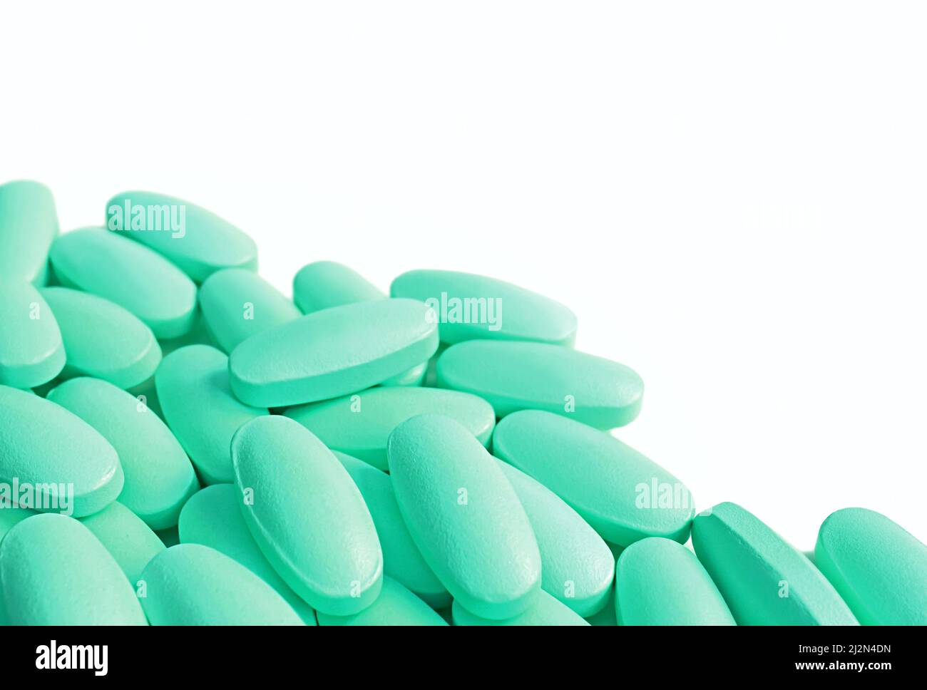 Heap of mint green supplement pills on white background with copy space ...