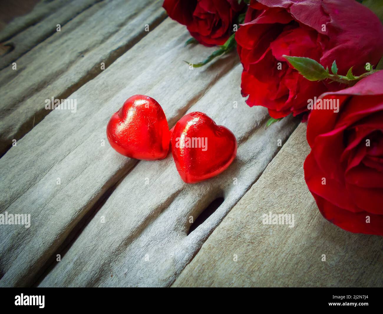 Red roses and two chocolate hearts for Valentine's Day on wooden table ...