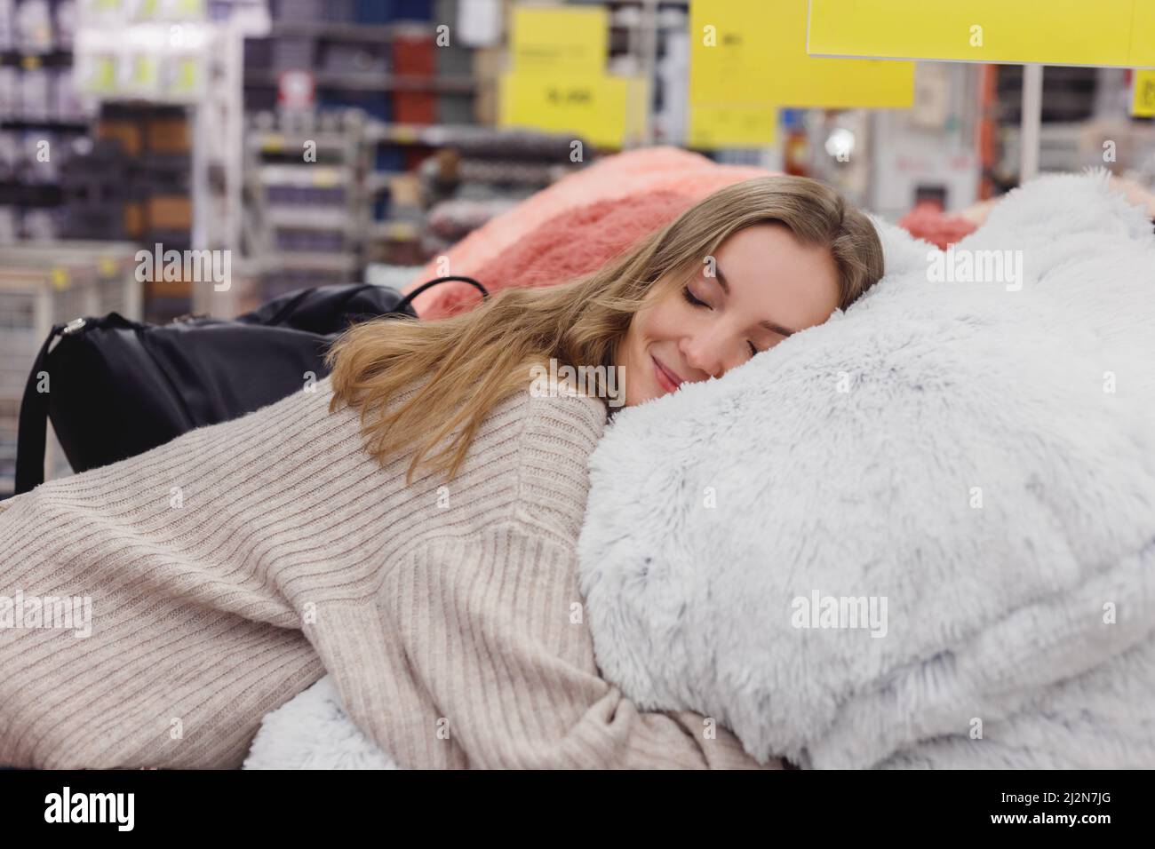 Woman in mall of large store lies down on plush cozy pillow and smiles ...