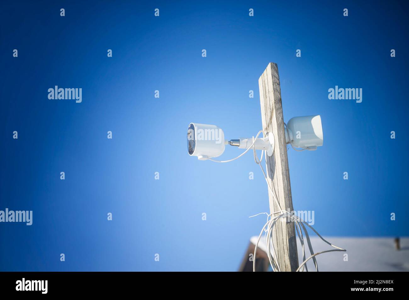 two surveillance cameras mounted on wooden post, sunny day shot Stock ...