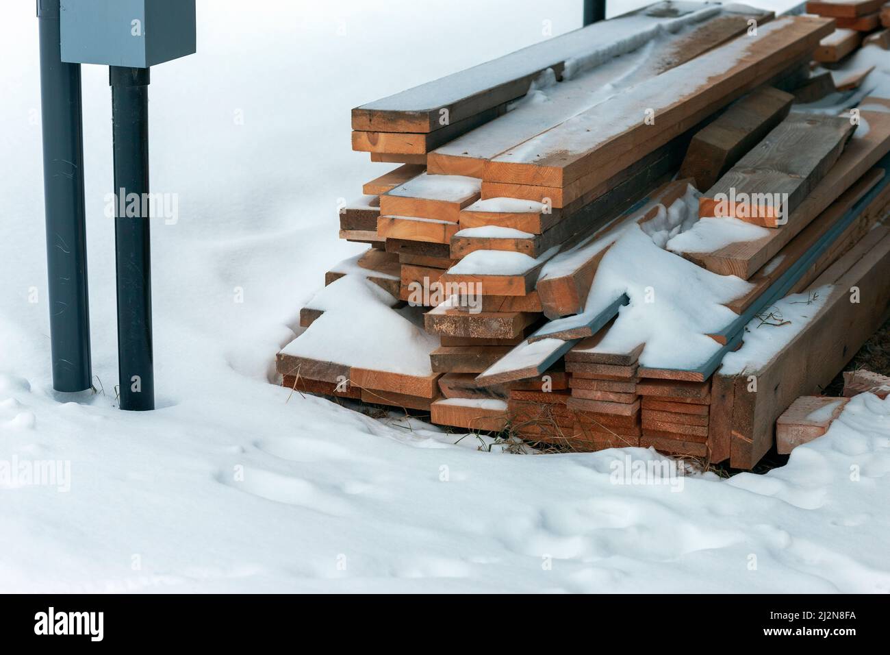 stack of construction materials and boards on the snow, winter scene ...