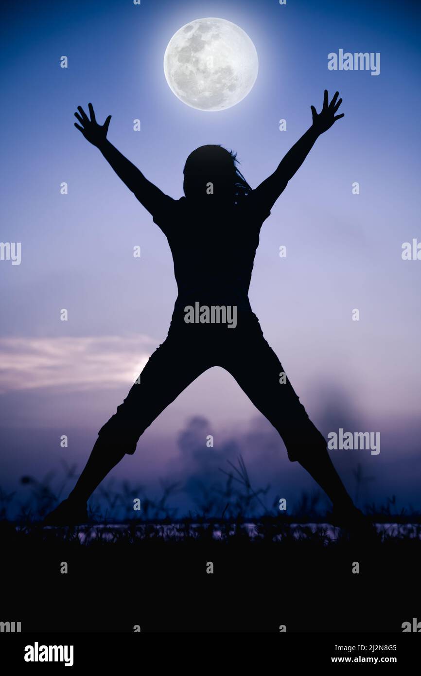 Silhouette back view of woman enjoying and jumping at riverside. Full ...