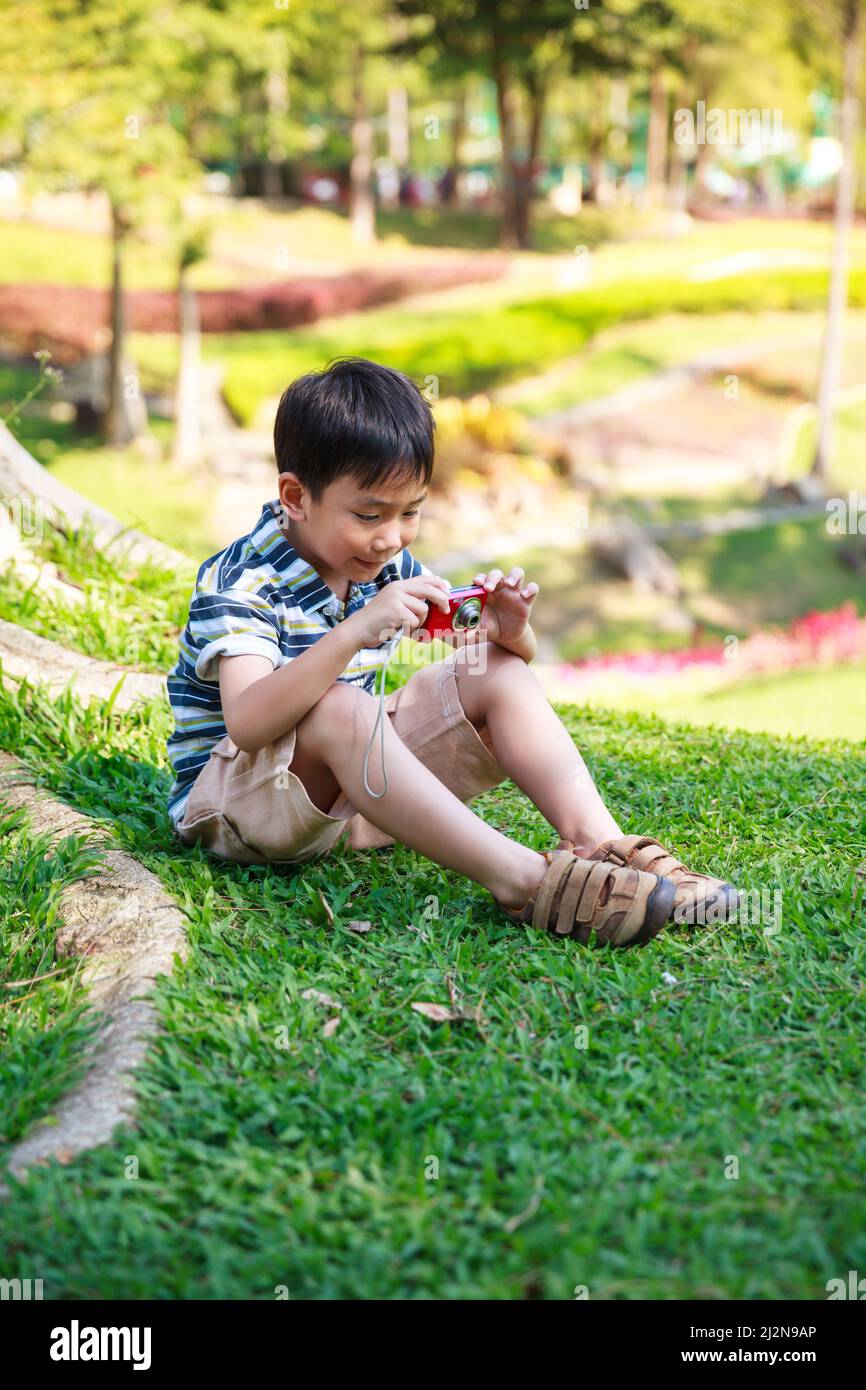 Happy asian boy with camera on nature background. Child relaxing outdoors in the day time at ...