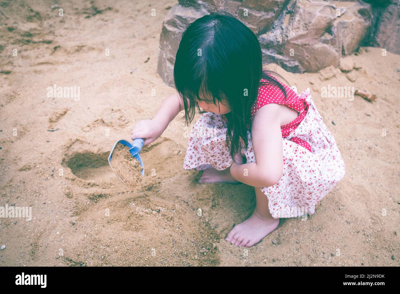 Happy child playing with sand. Adorable asian girl has fun digging in ...