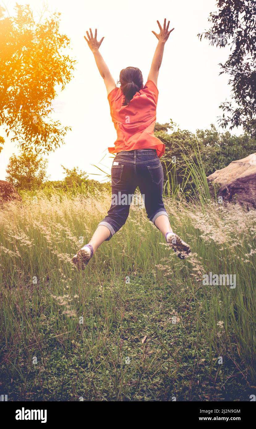 Back view of woman jumping at forest, outdoor with bright sunlight at ...