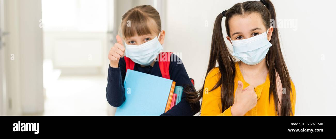 Cute little girls of primary hug each other with the mask on. School ...