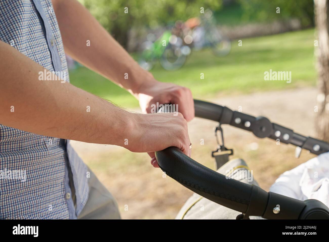 A young dad walking in the park with a baby in a stroller. Close-up of ...