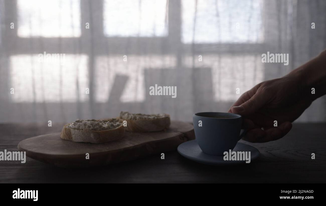 man hand take cup of espresso and ciabatta with cream cheese, wide ...