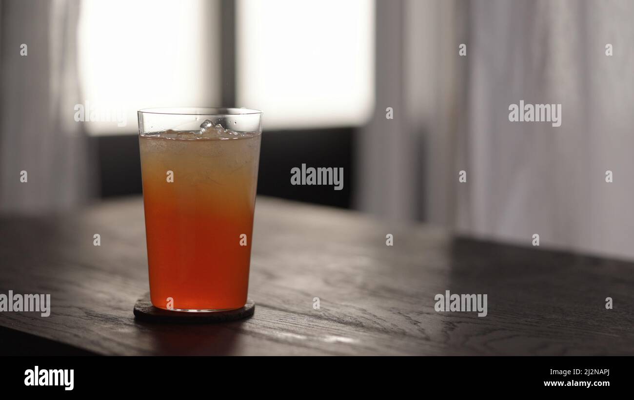 orange syrup in lemonade in tumbler glass with crushed ice on wood ...